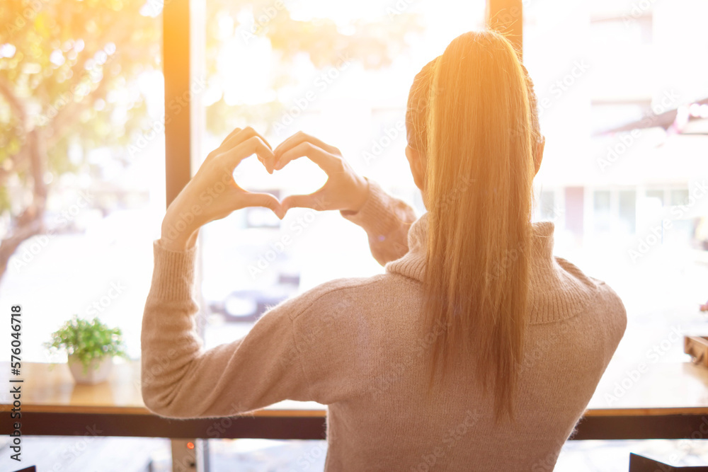 blurred background Young woman shows her hands up to form heart symbol ...