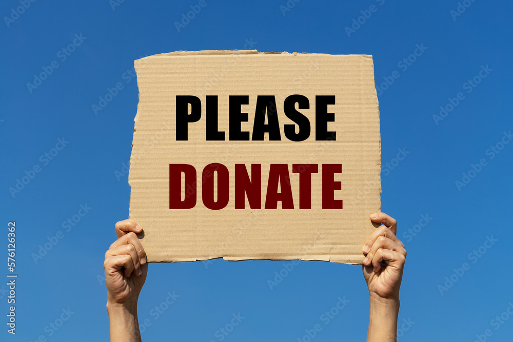 Please donate text on box paper held by 2 hands with isolated blue sky ...