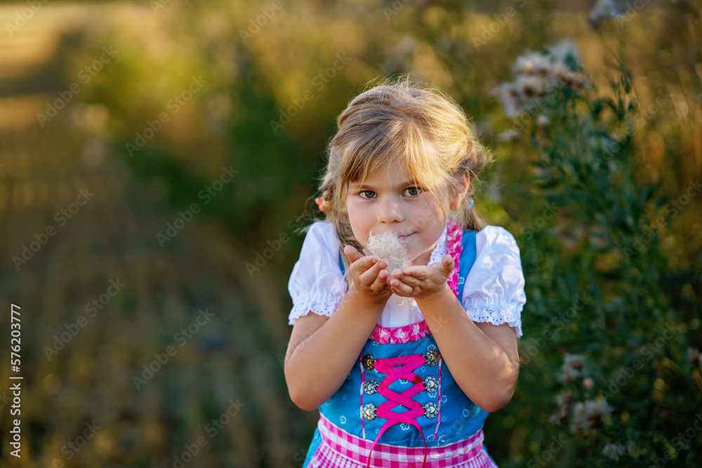 Cute little kid girl in traditional Bavarian costume in wheat field ...