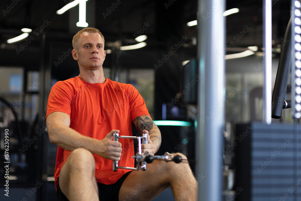 attractive strong handsome athlete man pumping up muscles in gym ...