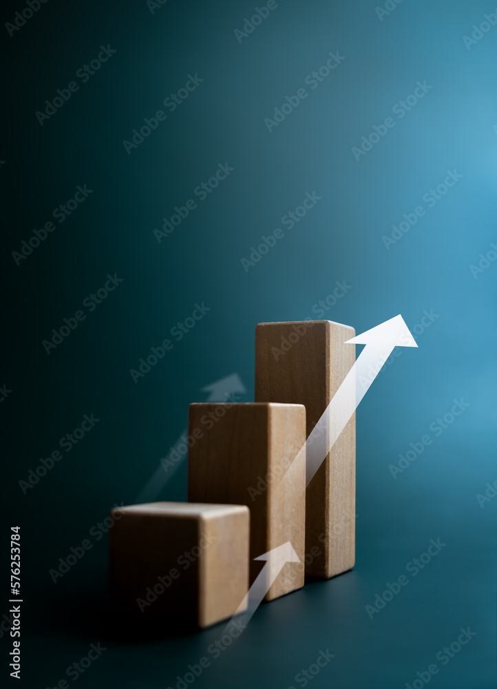 Rise up arrow on wooden cube blocks, bar graph chart steps on dark blue ...