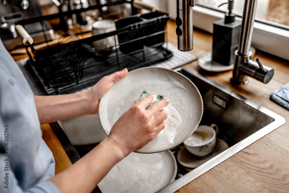 Girl washing dishes at kitchen at home Stock Photo | Adobe Stock