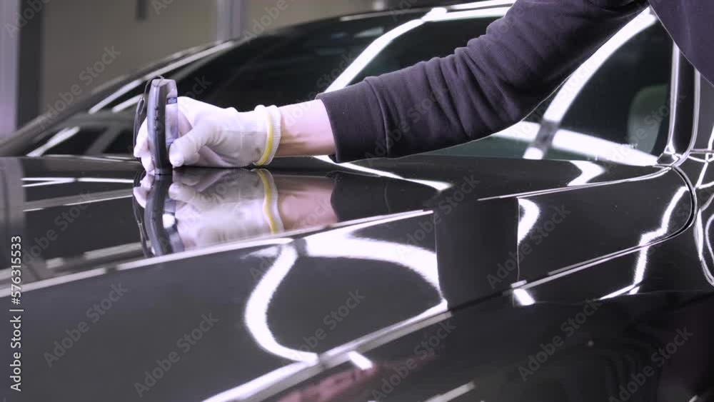 Worker measures a thickness of primer on a car's body using a thickness ...