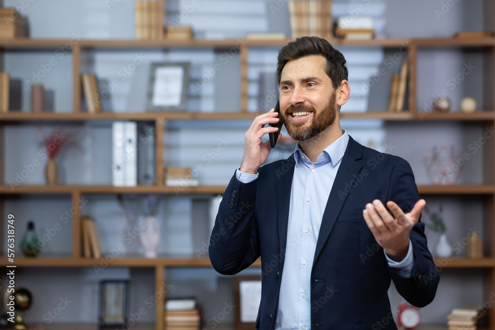 Mature successful boss happy with achievement talking on phone inside ...