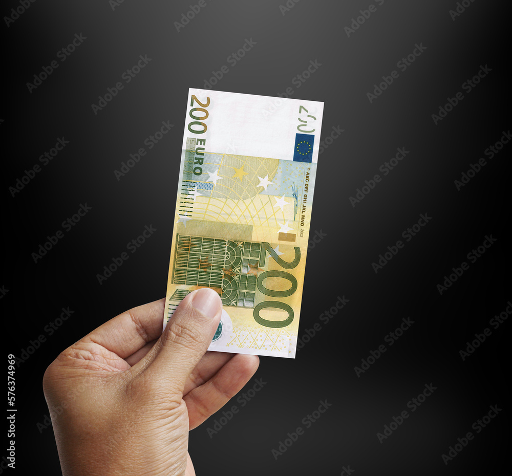 Male hand holding a 200 euro banknote in black background. Europe euro ...