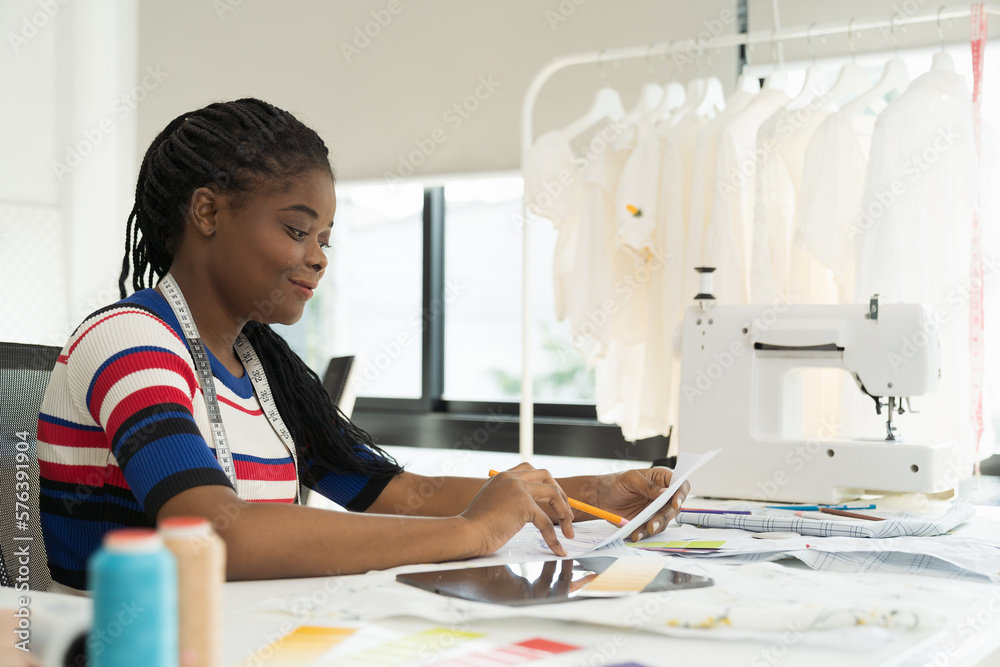 Smiling African American young female dressmaker working and choosing ...