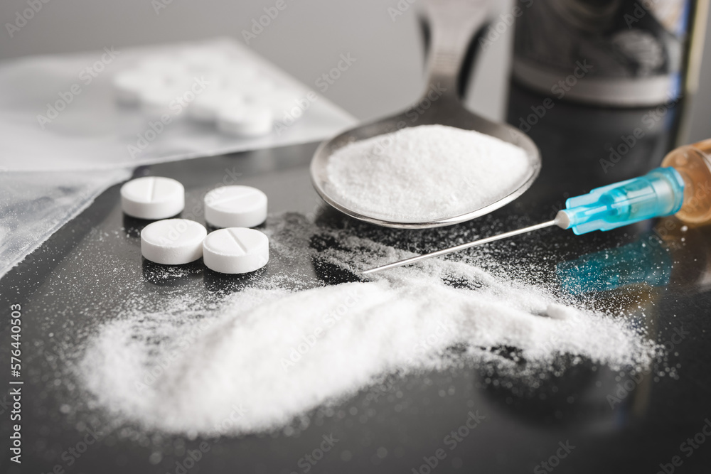 Drugs on dark background, cocaine or heroin white powder, white pills ...