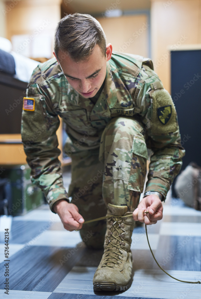 Brave is the man who wears combat boots. Shot of a young soldier tying ...
