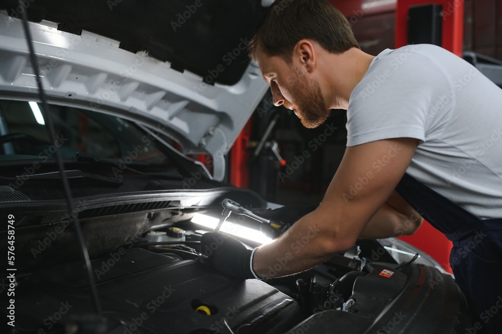 Handsome young male auto mechanic in special uniform clothes holding a ...