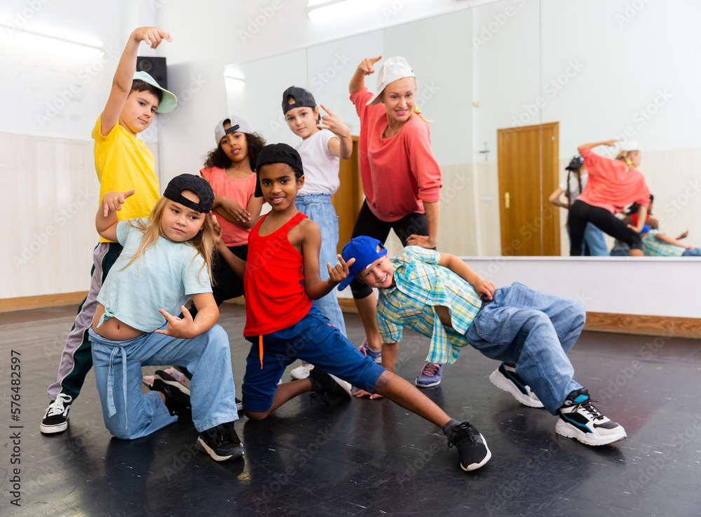 Portrait of cheerful preteen girl practicing dance movements with group ...
