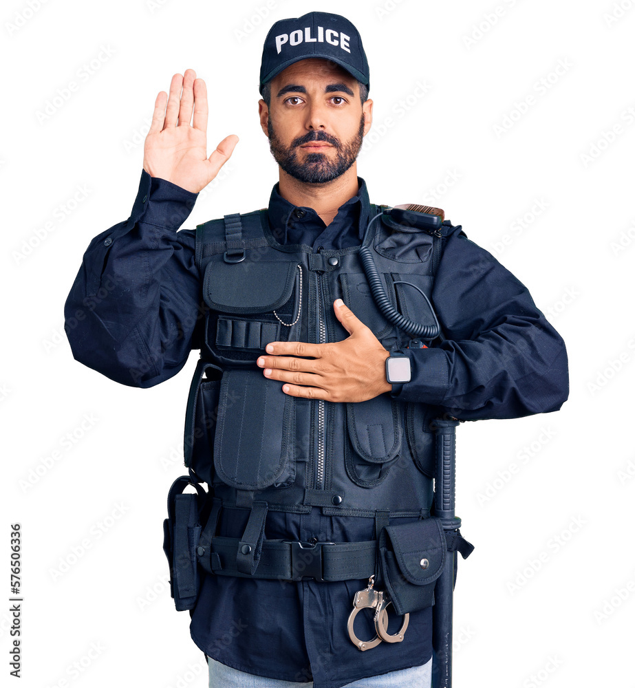Young hispanic man wearing police uniform swearing with hand on chest ...