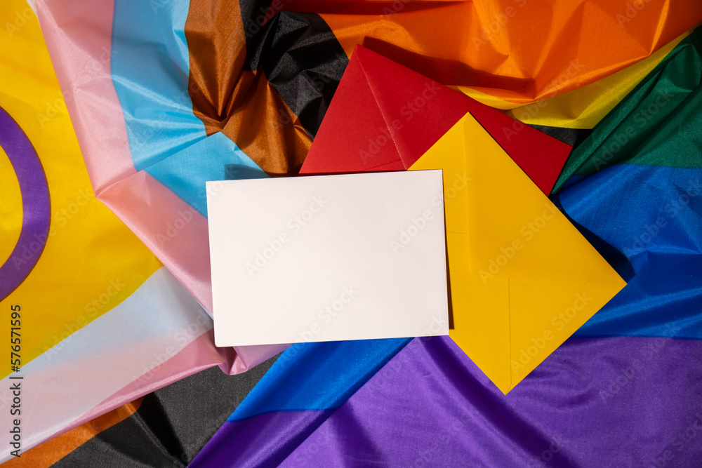 Empty paper blank on Rainbow LGBTQIA flag made from silk material. Mock ...