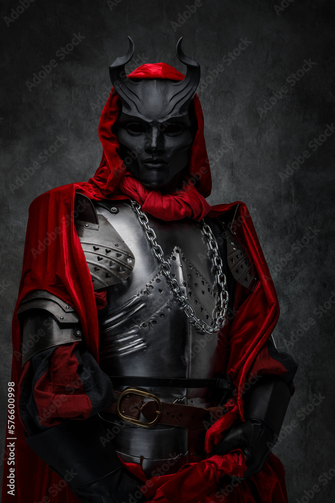 Studio shot of mystic prayer of dark cult dressed in silver plate armor ...