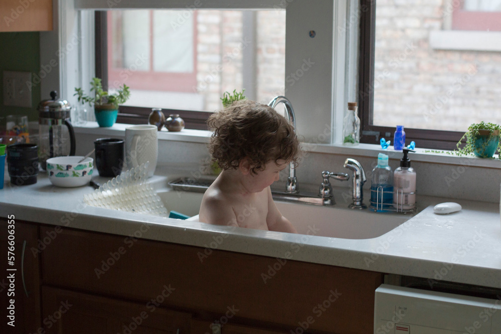 Boy taking bath in kitchen sink Stock Photo | Adobe Stock
