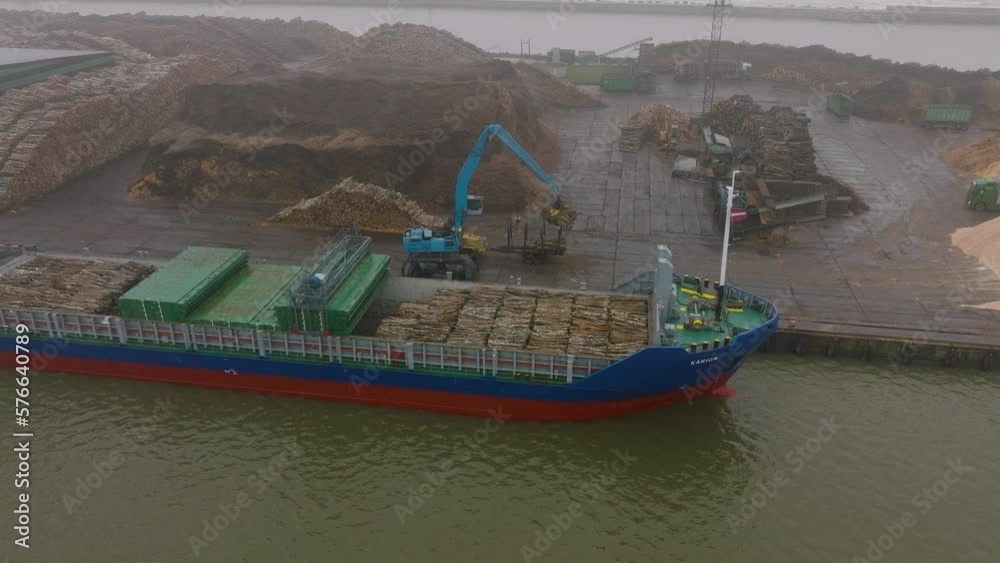 Aerial establishing view of wood terminal crane loading timber into the ...