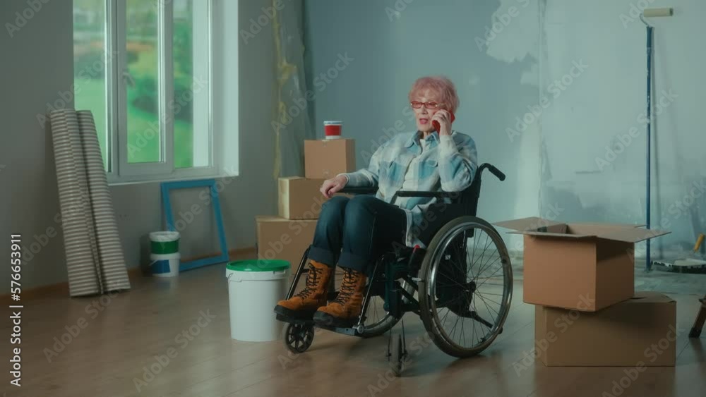 An elderly disabled woman moves in a wheelchair and talks on a mobile ...