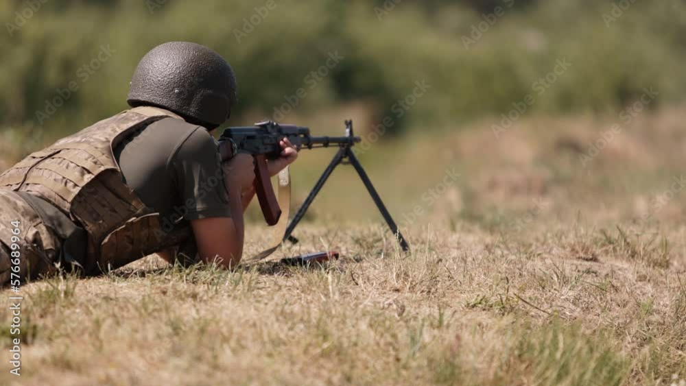 In green uniform vest, a military man unloads a machine gun, a soldier ...