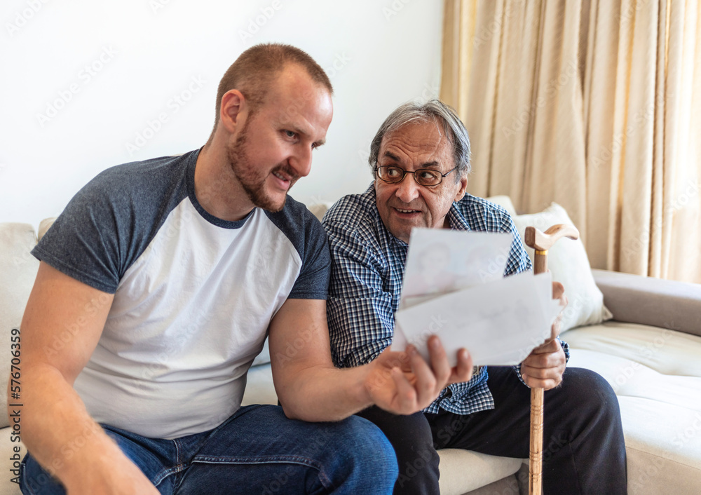 Foto de Senior father shows his adult son old photos of his father from ...