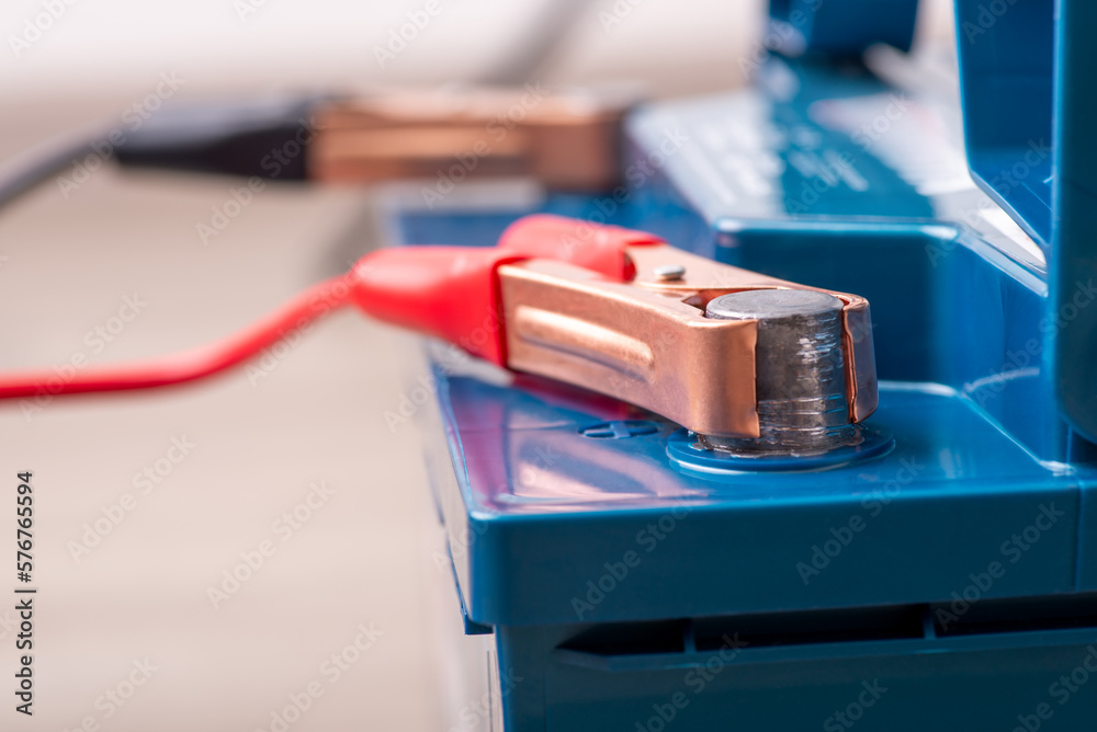 Red and black clamps connected to positive and negative terminals of ...
