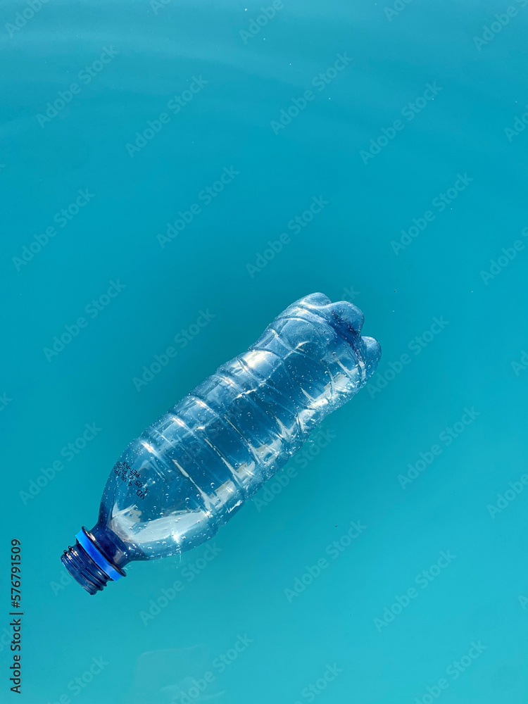 Single bottle thrown away in clear blue water, pollution mark ...