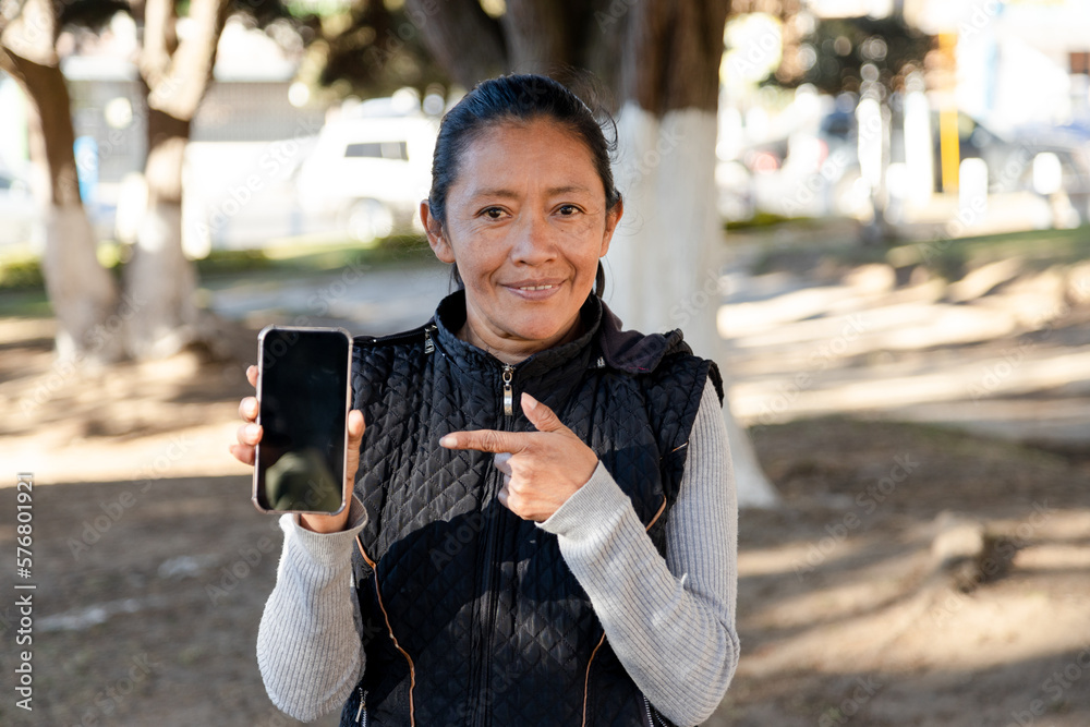 Hispanic woman pointing at a cell phone in the park - Mayan woman ...