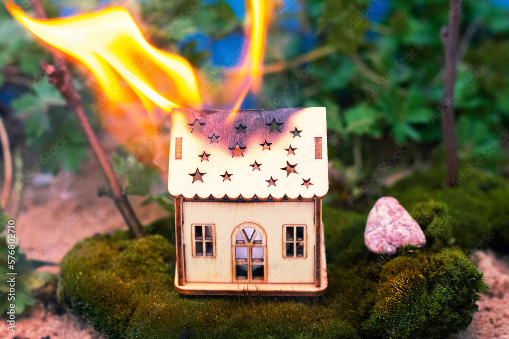 A toy wooden house is burning in nature. Fire concept. Fire safety ...