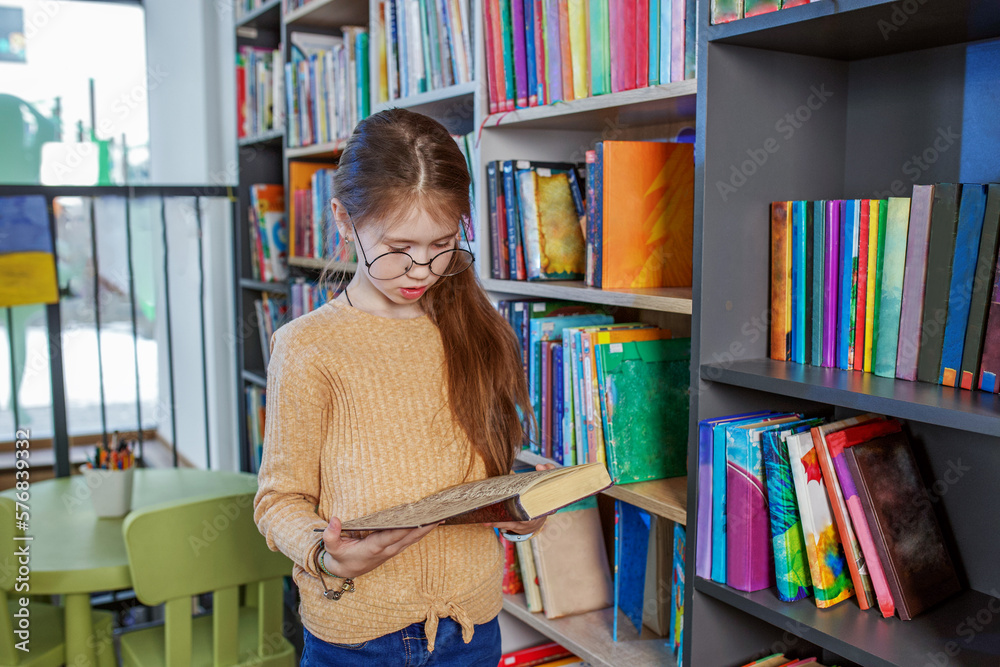 Child girl choosing book in school library. School education. Benefits ...