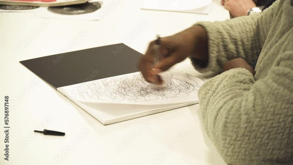 African woman close up hand drawing random circle patterns on paper ...