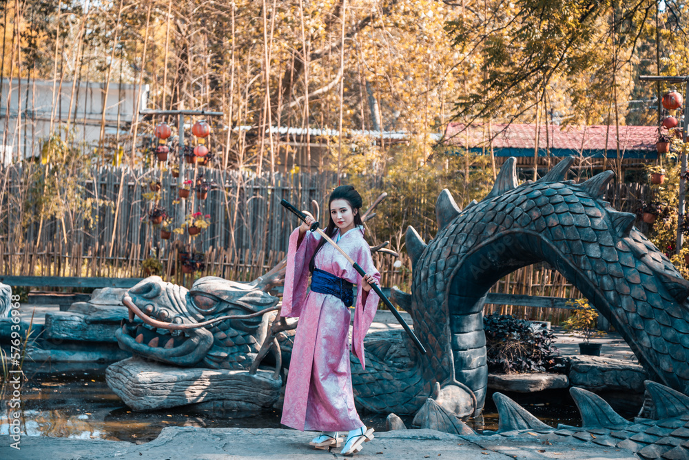 Japanese geisha in a traditional kimano with a fan and armed with a ...