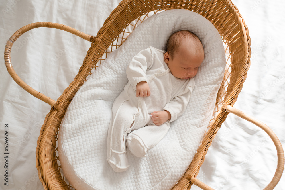 First days of little baby infant sleeping in straw crib wearing white ...