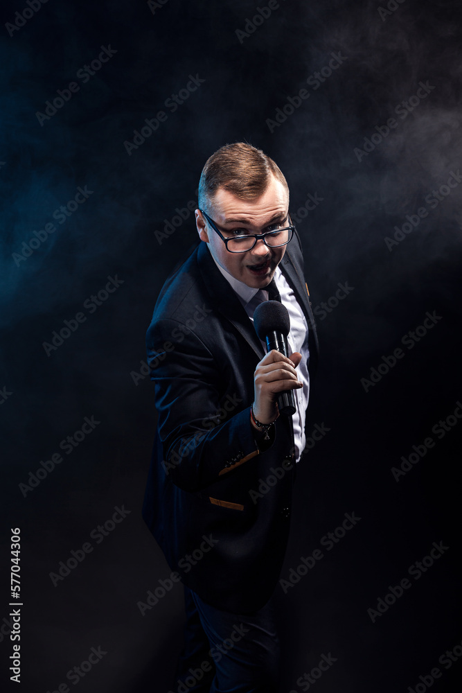 Stylish man in glasses with microphone on black background, actor ...