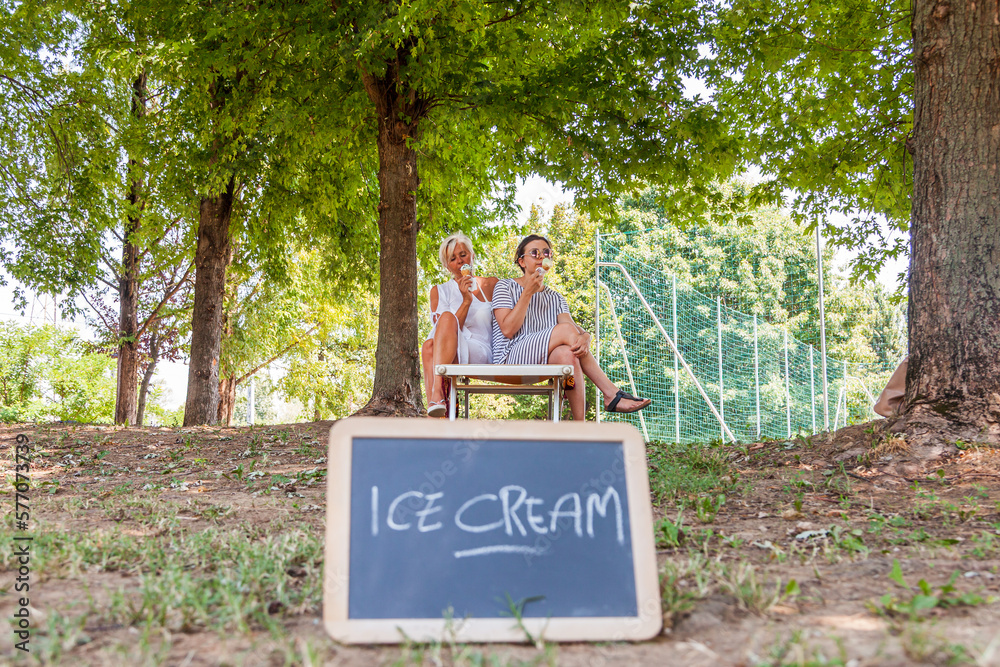 Modern Mom And Young Daughter Eating Ice Cream Sitting On A Deckchair