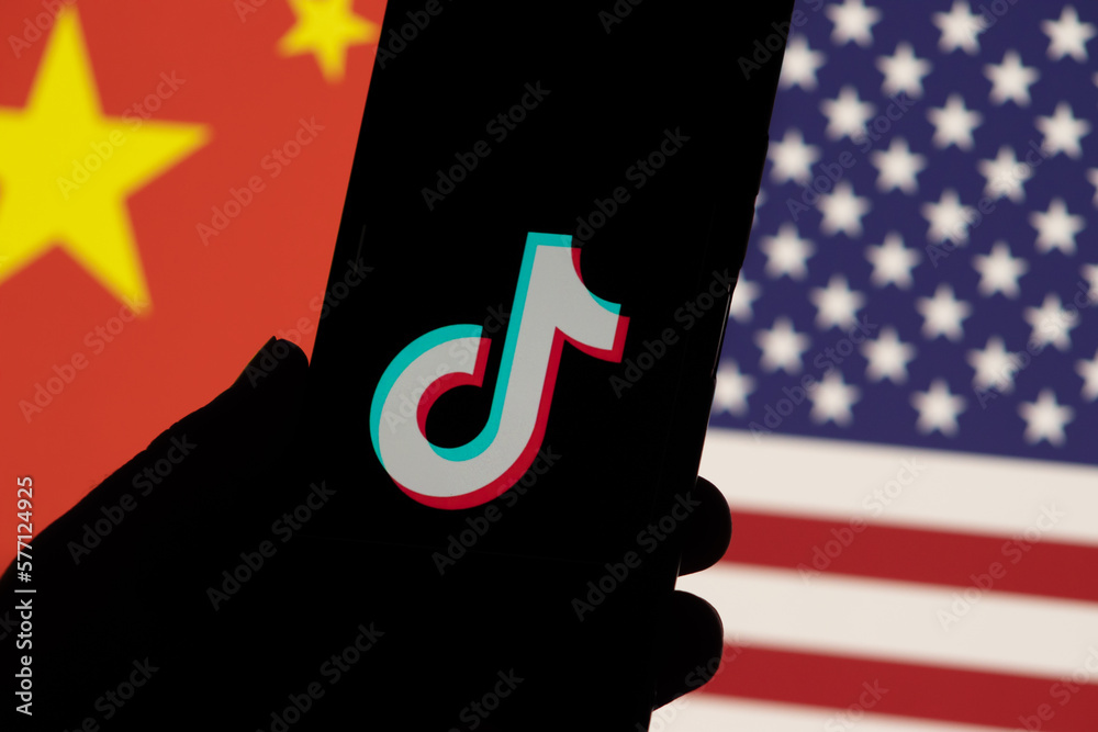 Smartphone with TikTok brand logo on screen and USA vs China flag ...