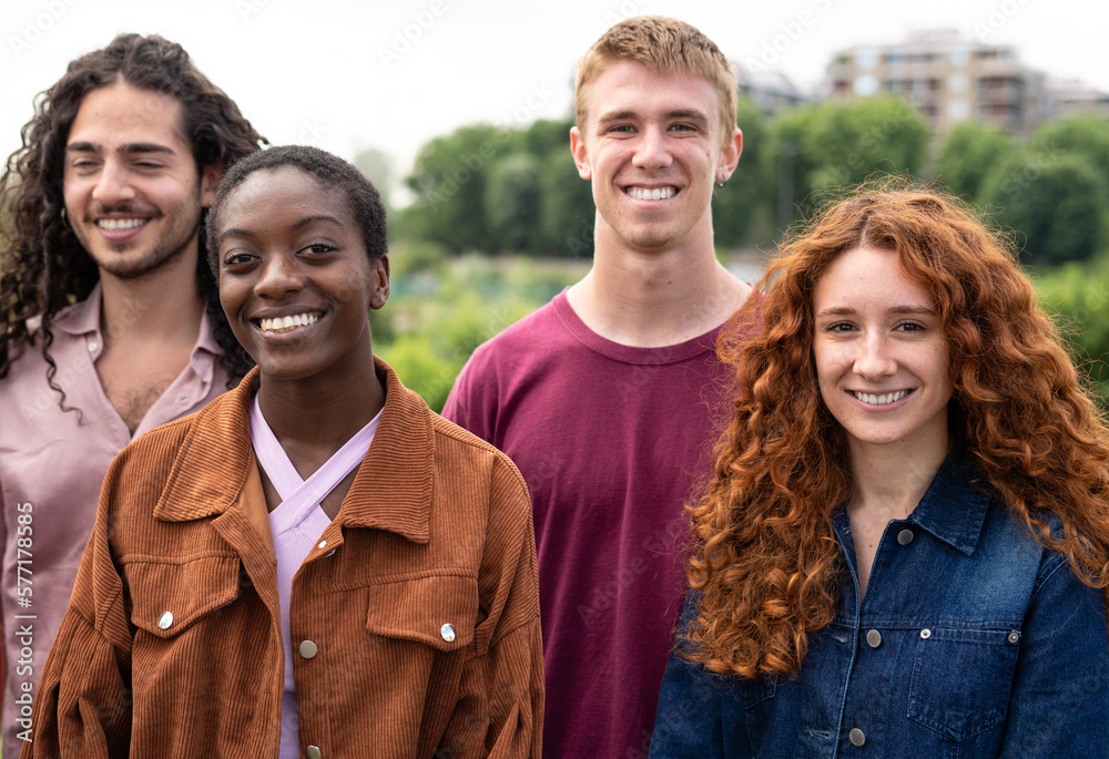 A group of multicultural friends laughing together on a park outdoor ...