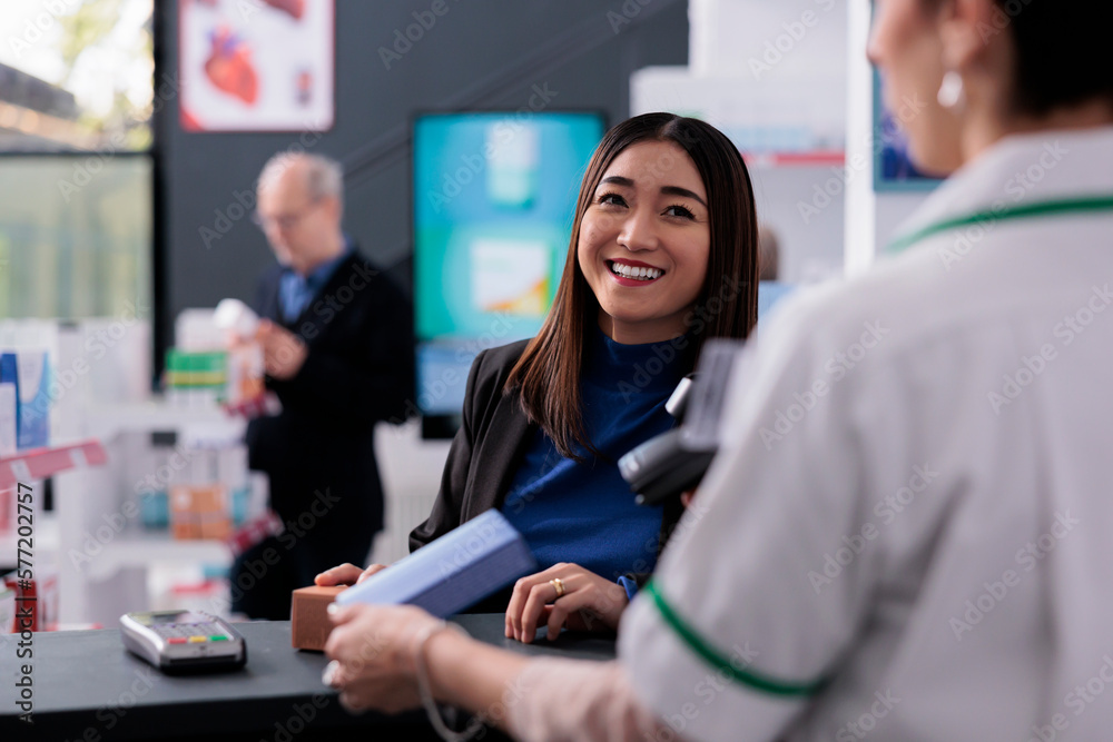 Foto de Smiling woman buying medicaments and talking to cashier at ...