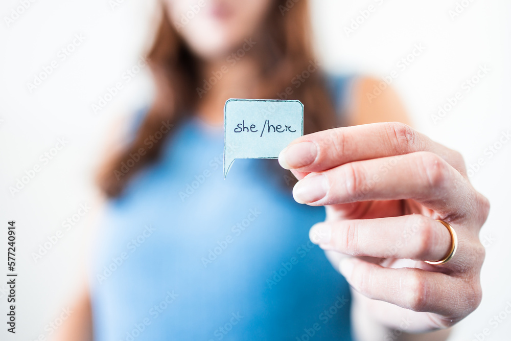 woman holding gender identity pronouns She Her on paper speech bubble ...