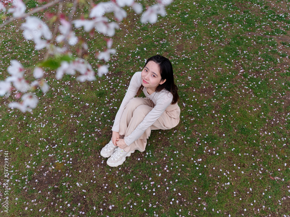 Outdoor portrait of beautiful young Chinese girl sitting on meadows ...