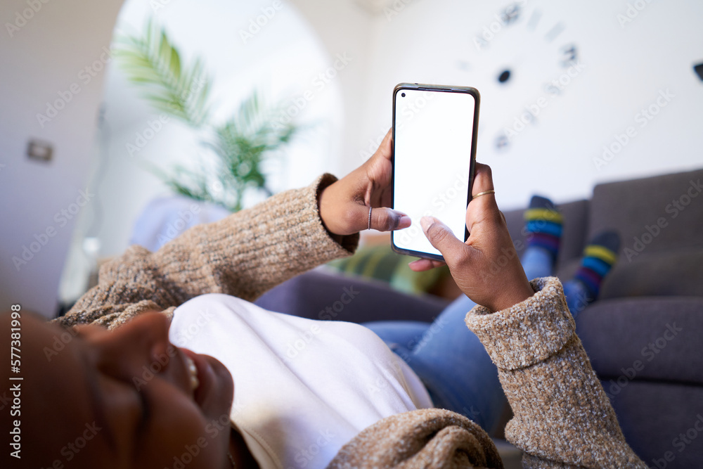 Young black woman using smartphone while lying and relaxing on the ...