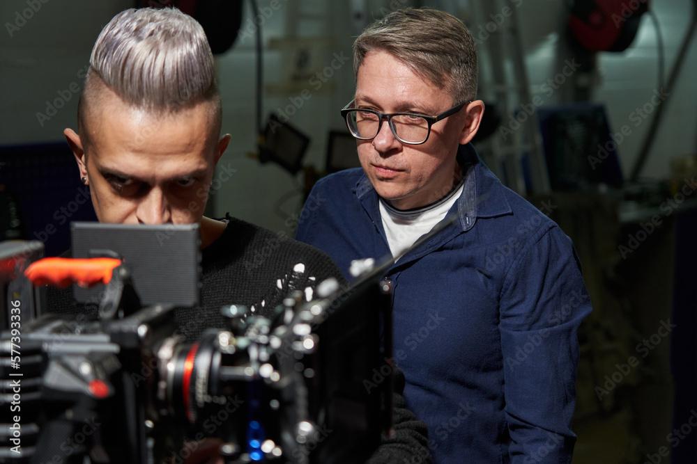 two caucasian male director and cameraman looking at the monitor screen ...