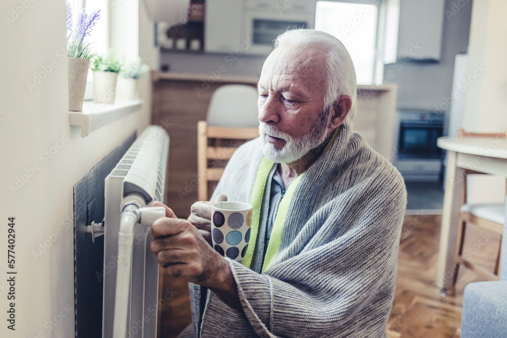 Man adjusting heater on a chilly winter day, energy and gas crisis ...