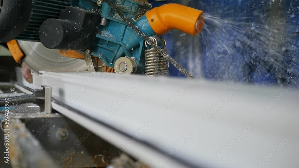 Close-up of a white pvc profile being cut in a factory using a circular ...