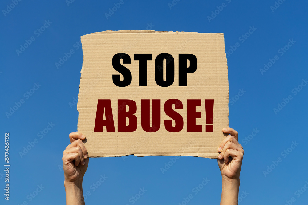 Stop abuse text on box paper held by 2 hands with isolated blue sky background. This message ...