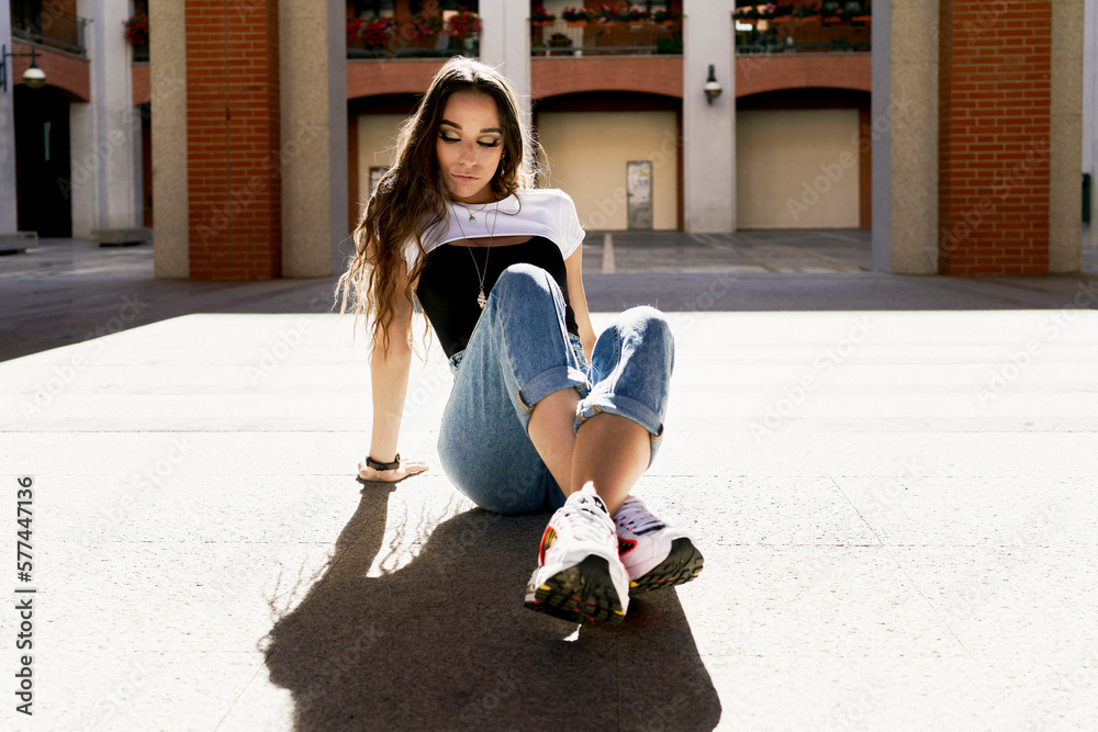 Adult woman looking down posing sitting on the floor hands on knees ...