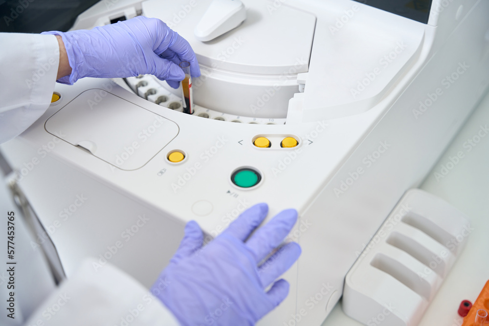 Laboratory assistant puts a test tube into an immunochemiluminescent ...