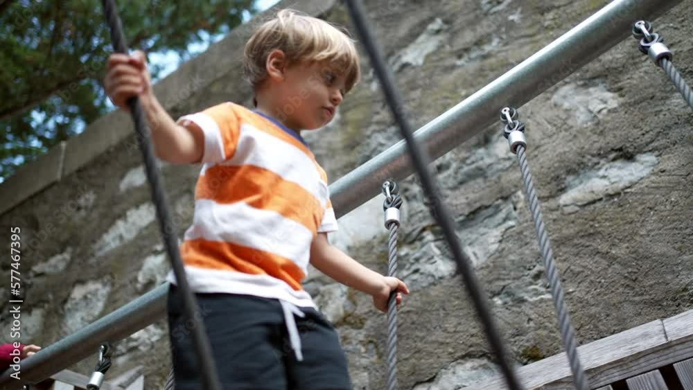 Active child staying in balance crossing playground bridge outside. One ...