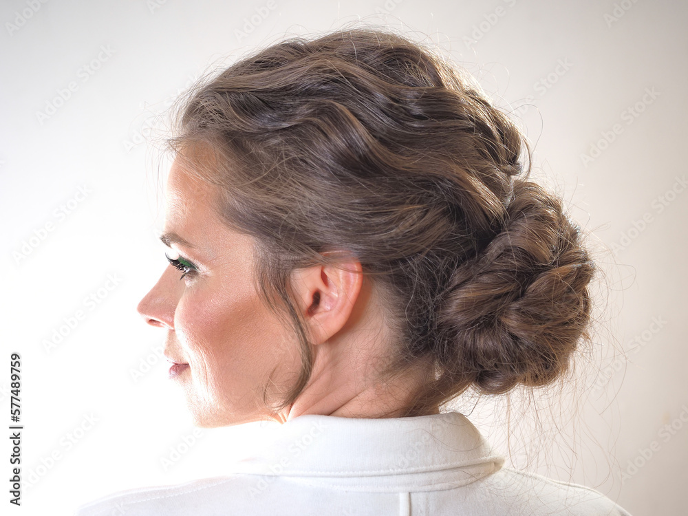 A beautiful girl gathered her wavy hair in a low bundle. Modern festive ...