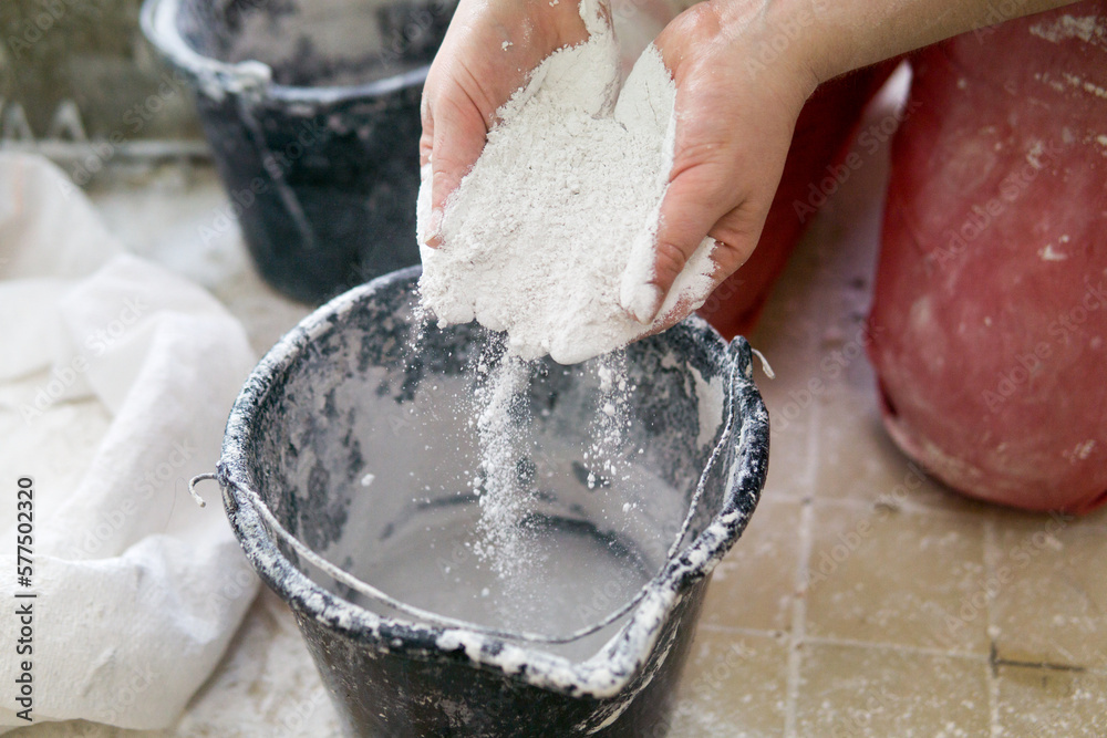 Adding the plaster powder to the water in a mixing container by ...