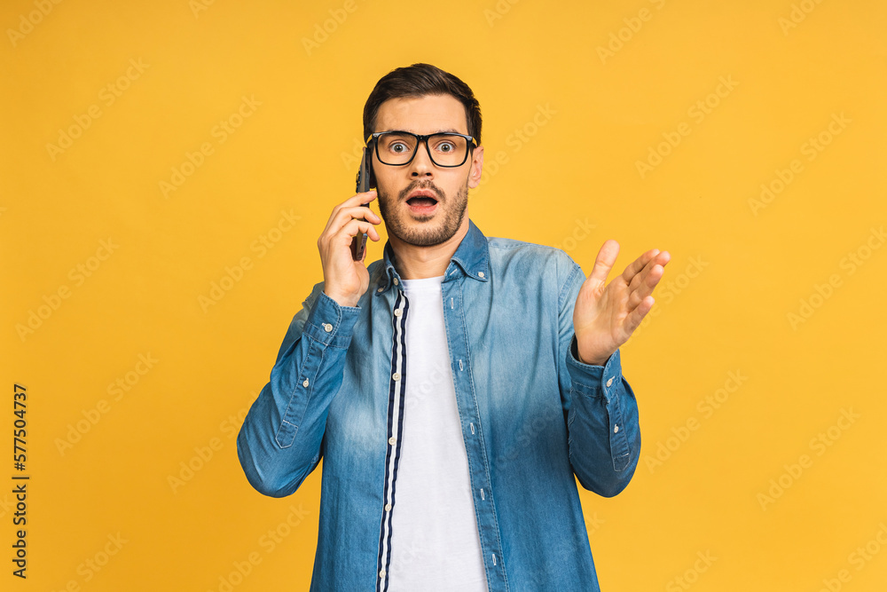 Young handsome man talking on smartphone isolated against yellow ...
