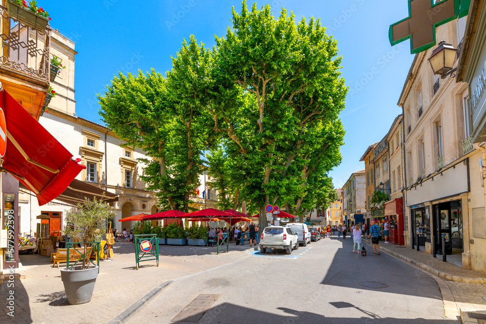 A small town square with shops, trees, and sidewalk cafes in the ...