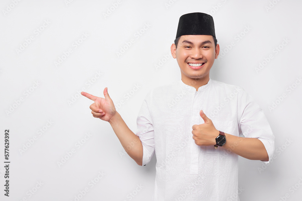 Happy smiling handsome young Asian Muslim man pointing finger aside ...